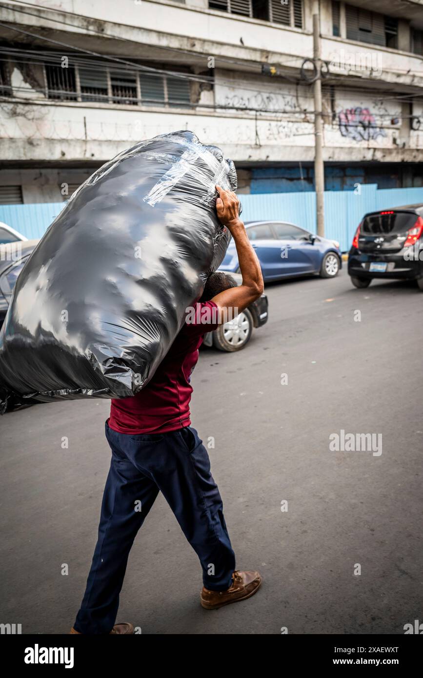 Street scen in the city centre - man carrying a heavy sack, San ...