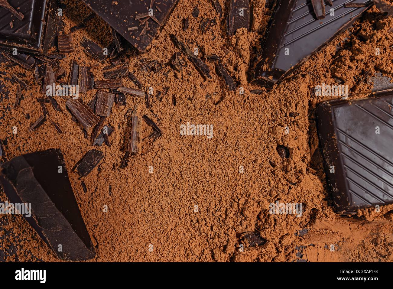 Slices and shaves of dark bitter chocolate scattered on cocoa powder ...