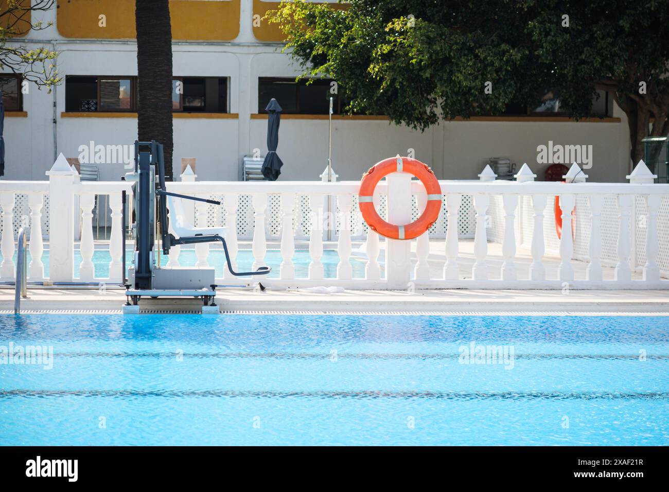 A pool with a lifeguard chair and a red and orange life preserver Stock ...