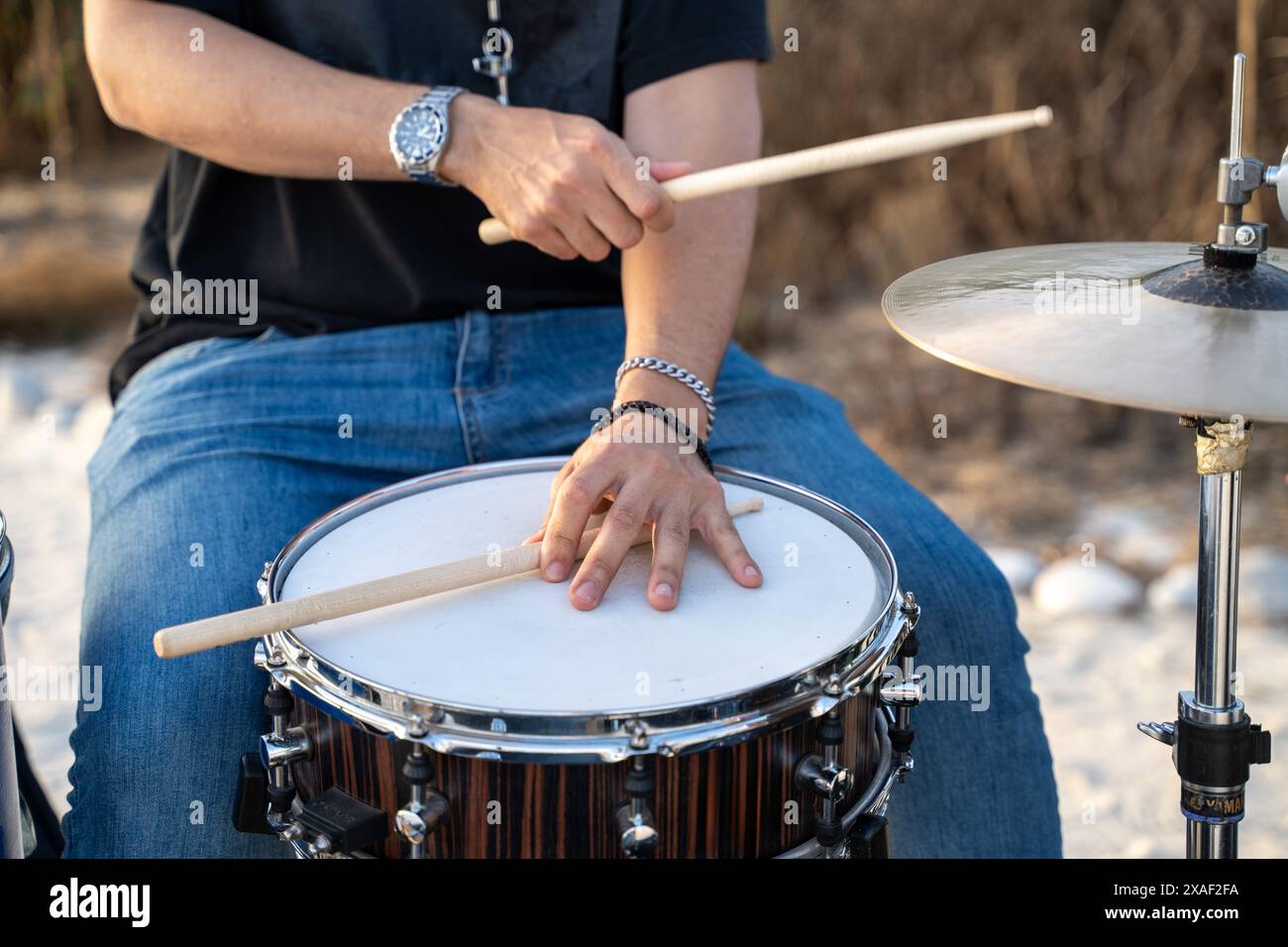 Close-up of a drummer playing a snare drum during an outdoor music session. Musician’s hands are ...