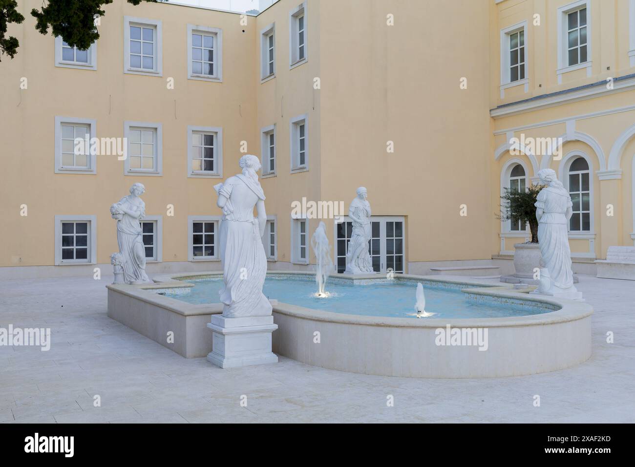Photo of an inner courtyard of ancient beige building with fountain and ...