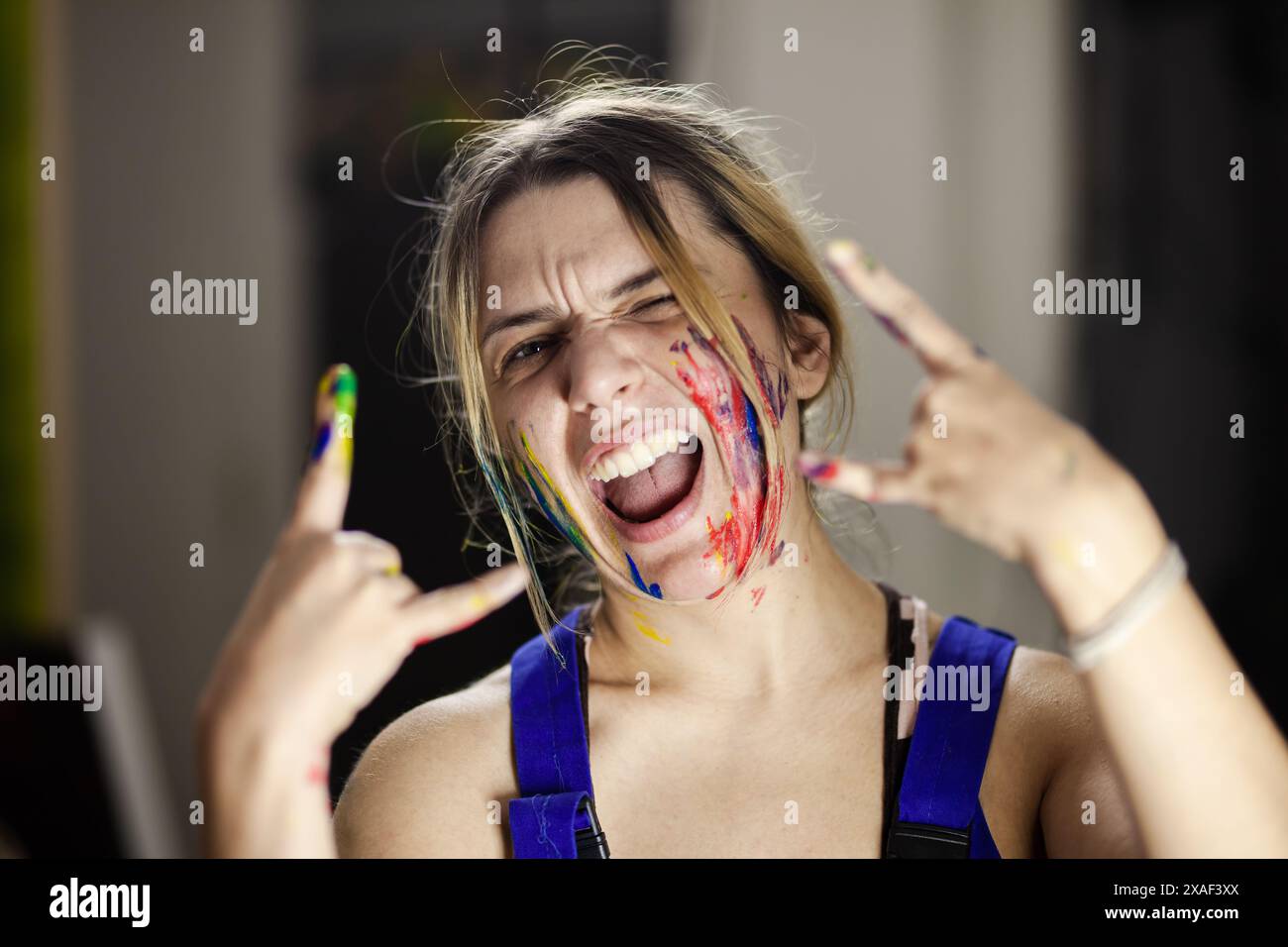 An exuberant female painter with her face and hands splattered with ...