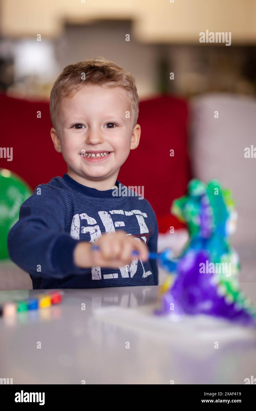A cheerful young boy enjoying his playtime with vibrant dinosaur toys ...