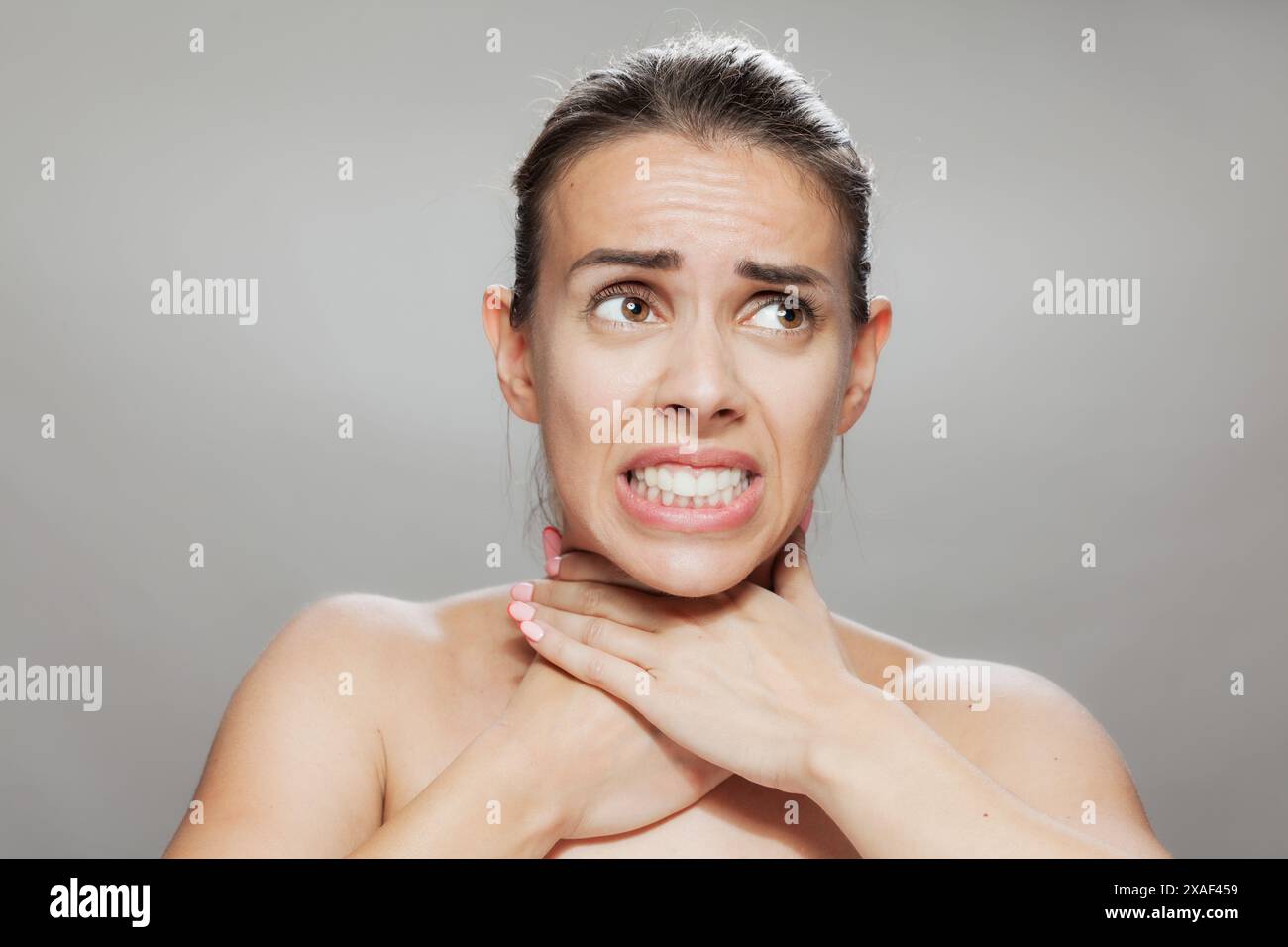 Concerned young female showing signs of stress and fear, clutching her ...