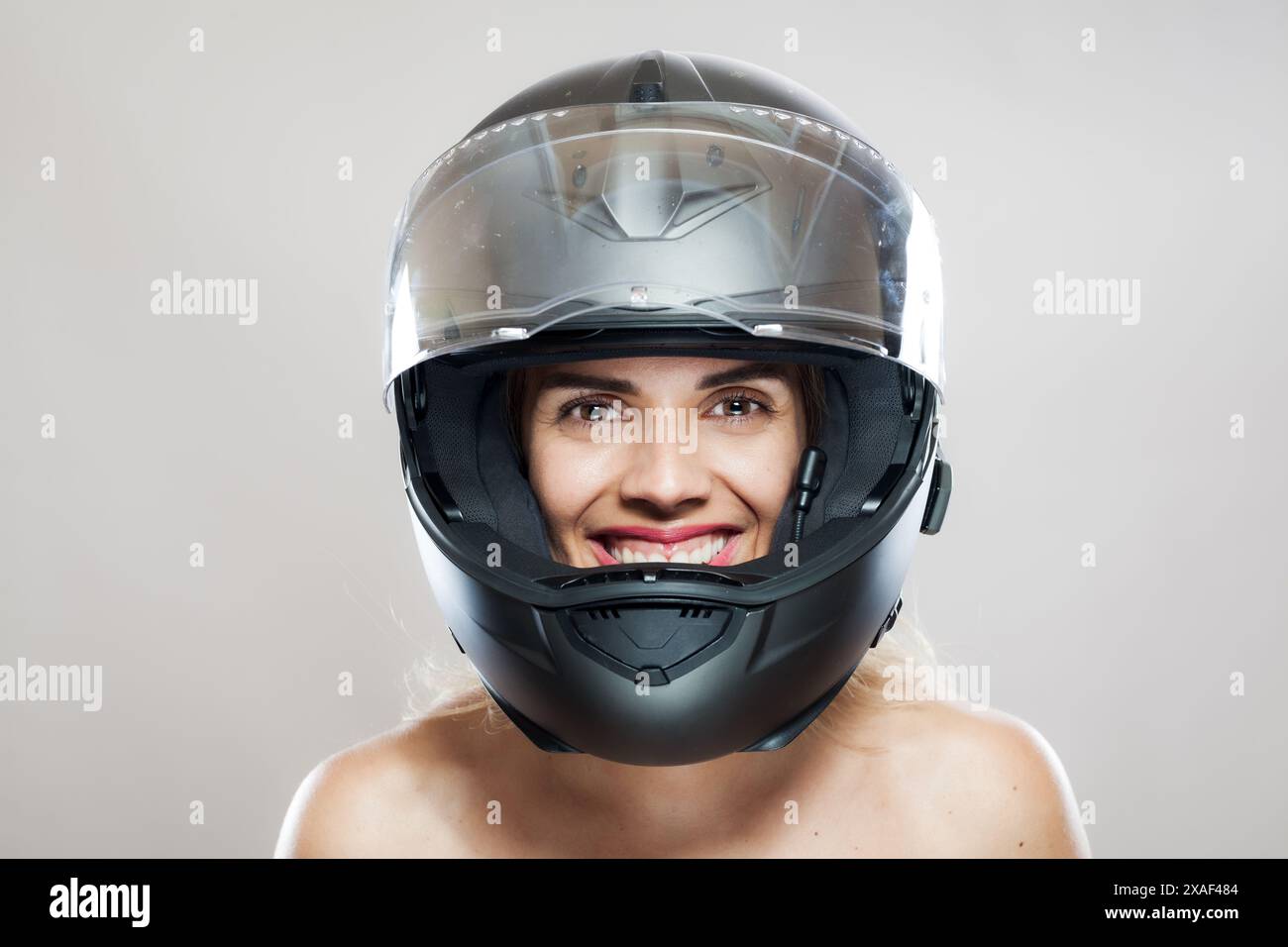 A cheerful woman smiles broadly while wearing a contemporary black motorcycle helmet ...