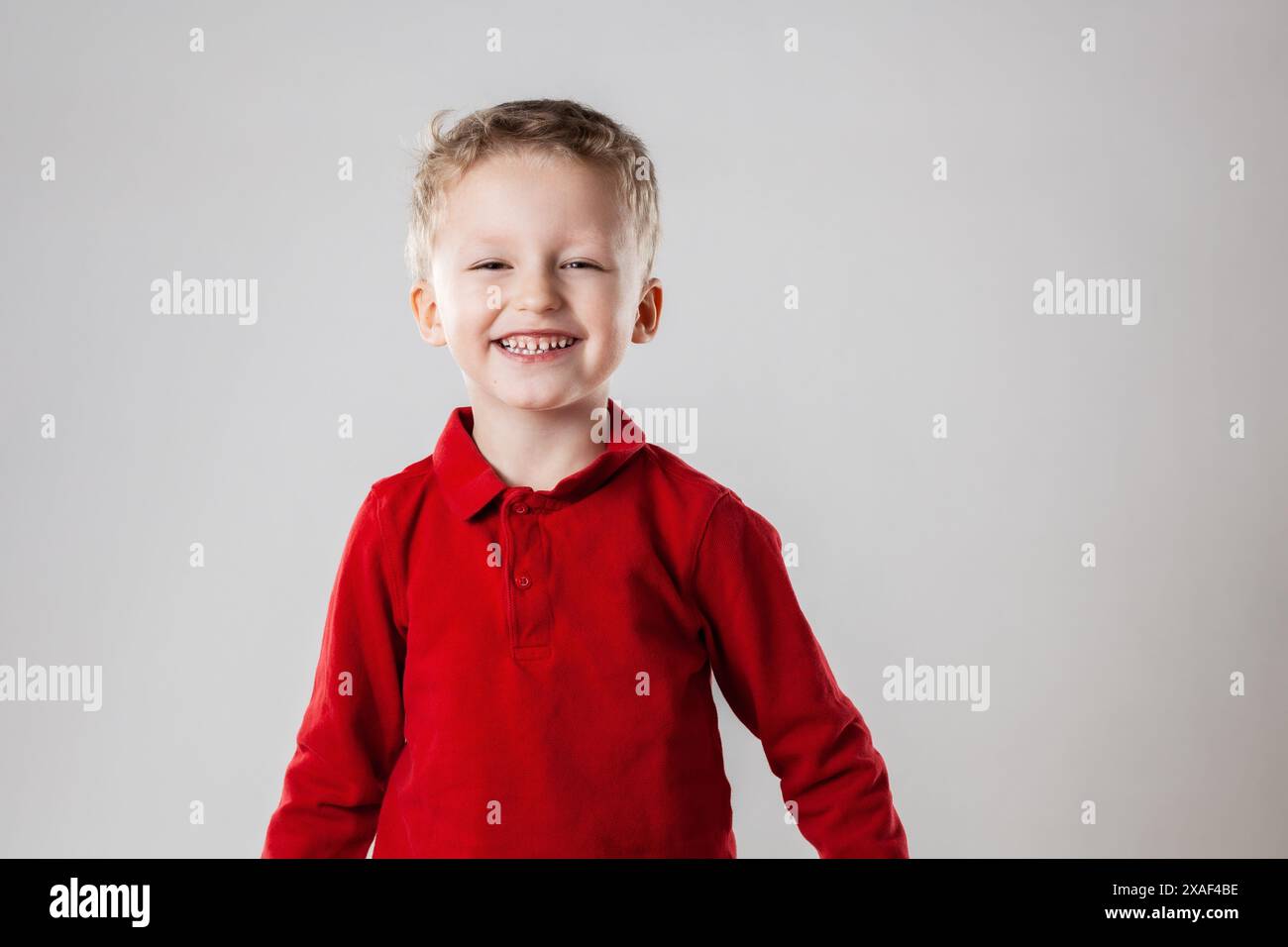 Portrait of a happy little boy standing upright smiling and looking at ...