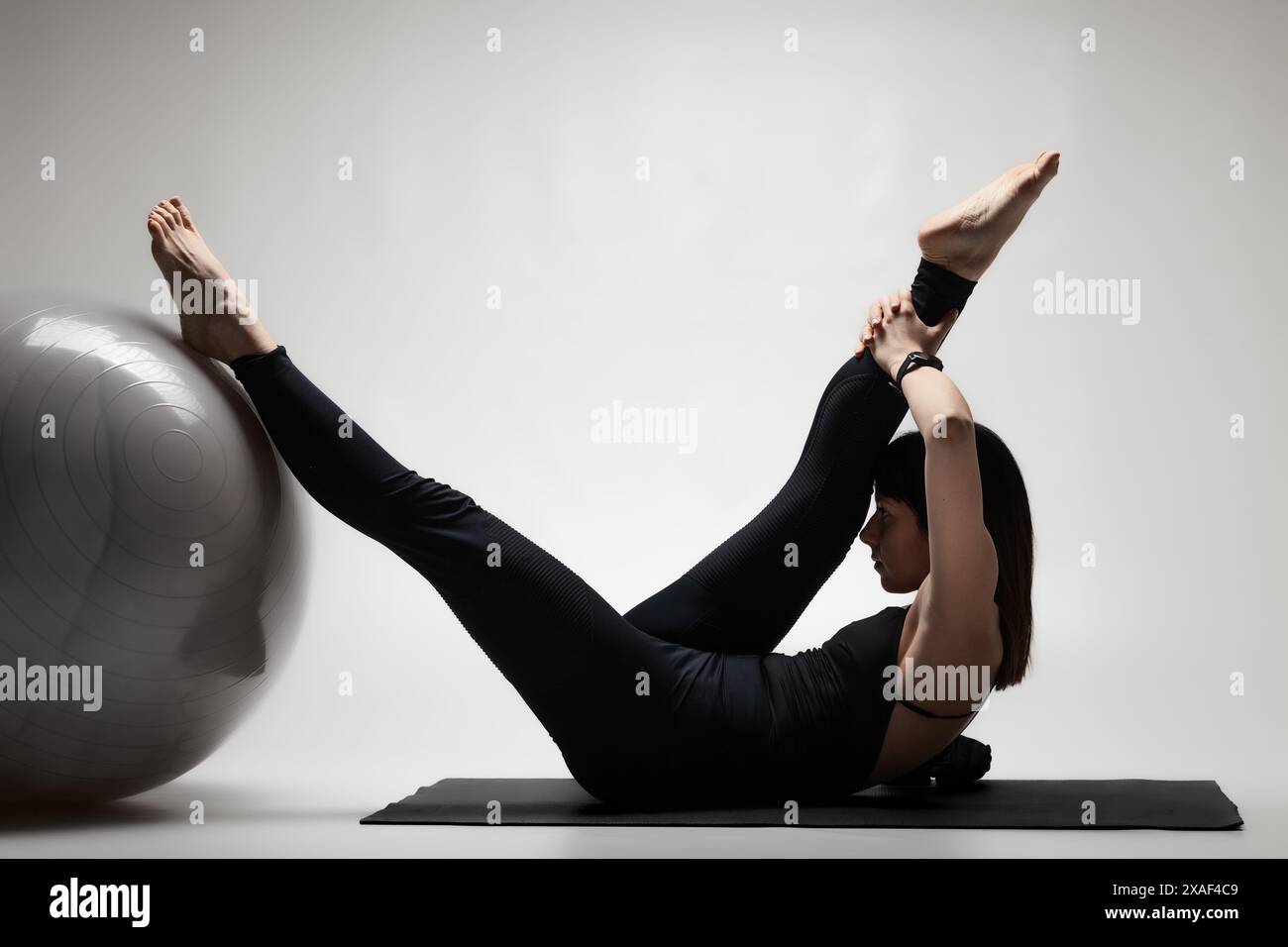 A young woman demonstrates flexibility during a yoga session, using a ...