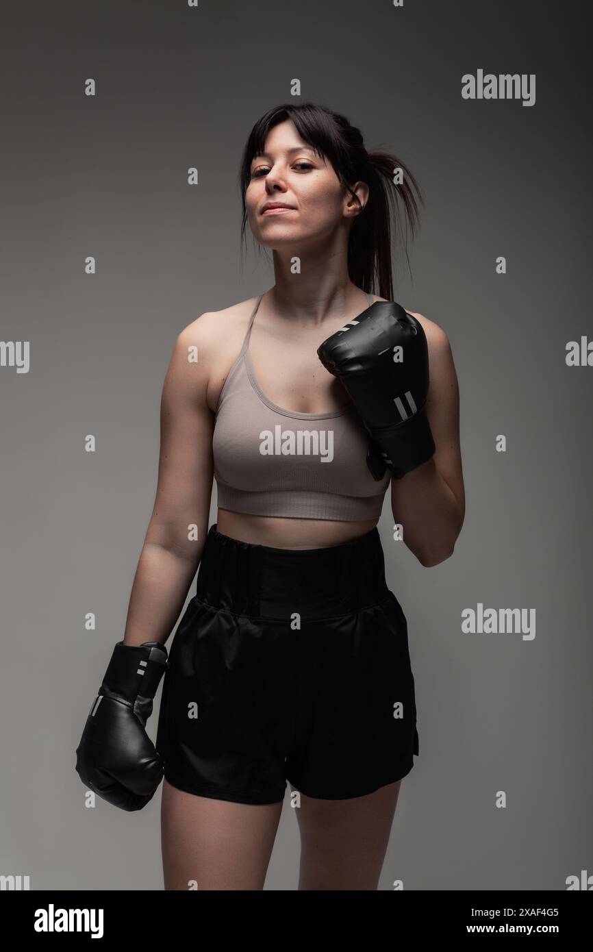 A young woman stands poised and ready in boxing attire, exuding ...