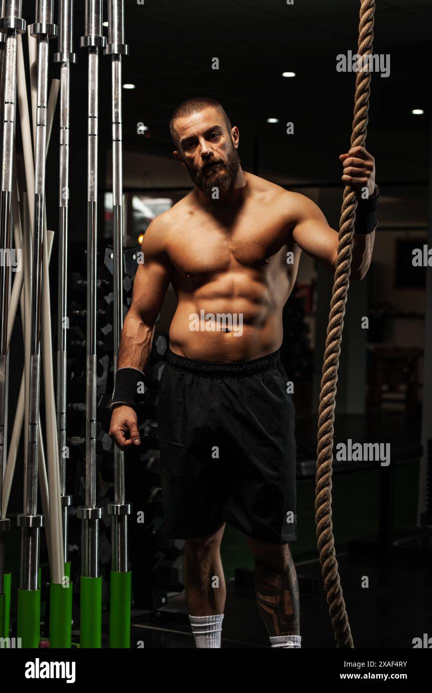 Focused and fit muscular man with a beard stands in a gym, gripping a ...