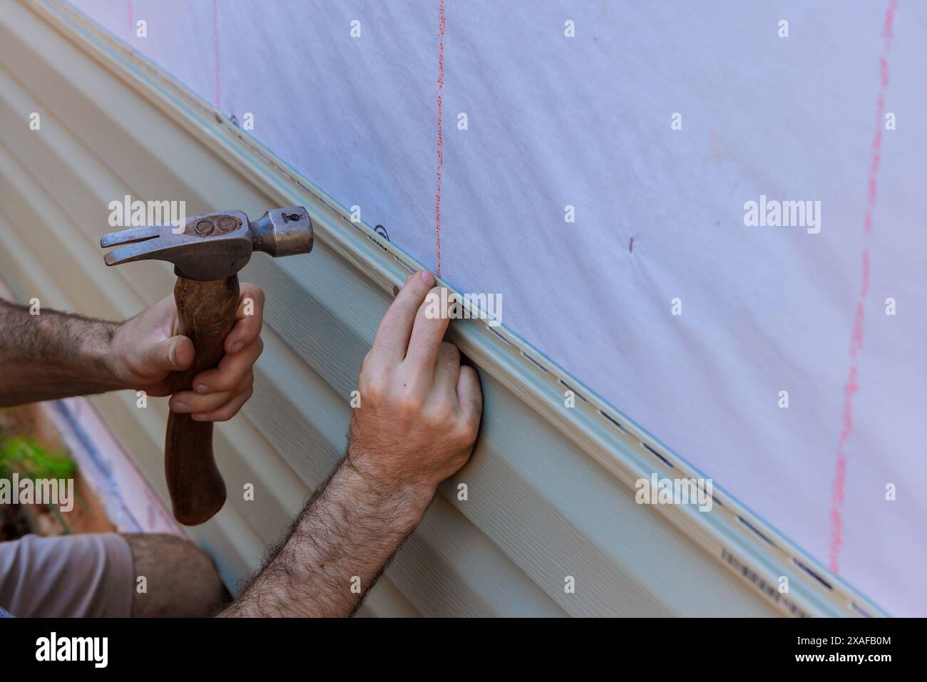 Handyman installs vinyl PVC siding on new home facade during ...