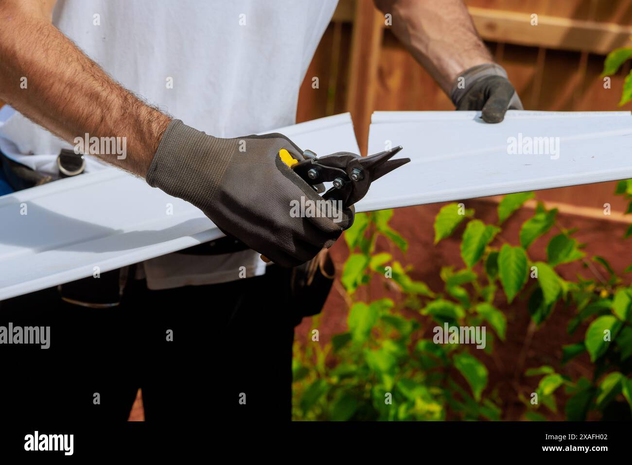 Craftsman cuts vinyl siding panel to desired size before installing it ...