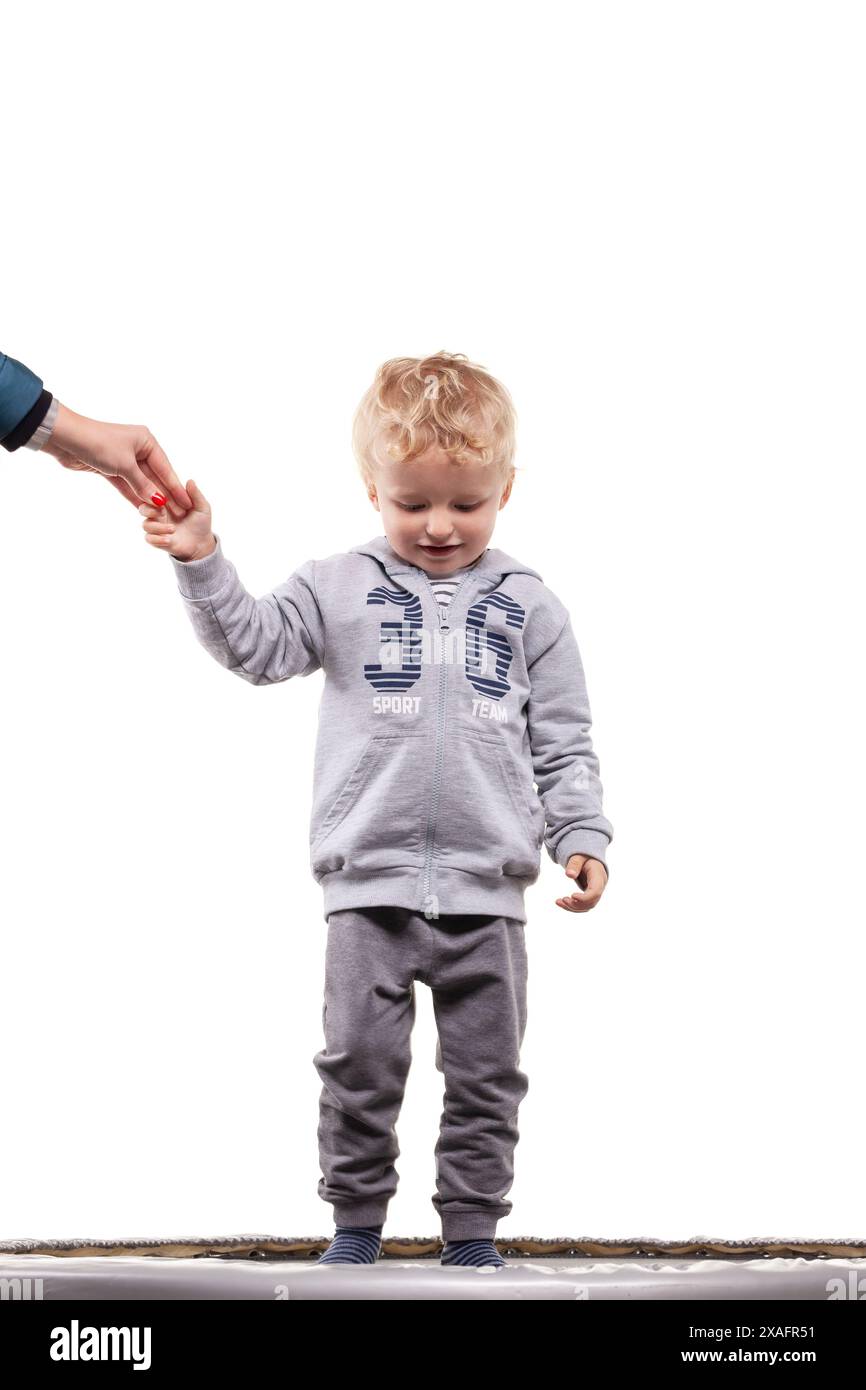 Adorable toddler boy dressed in gray sports outfit holding an adult's ...