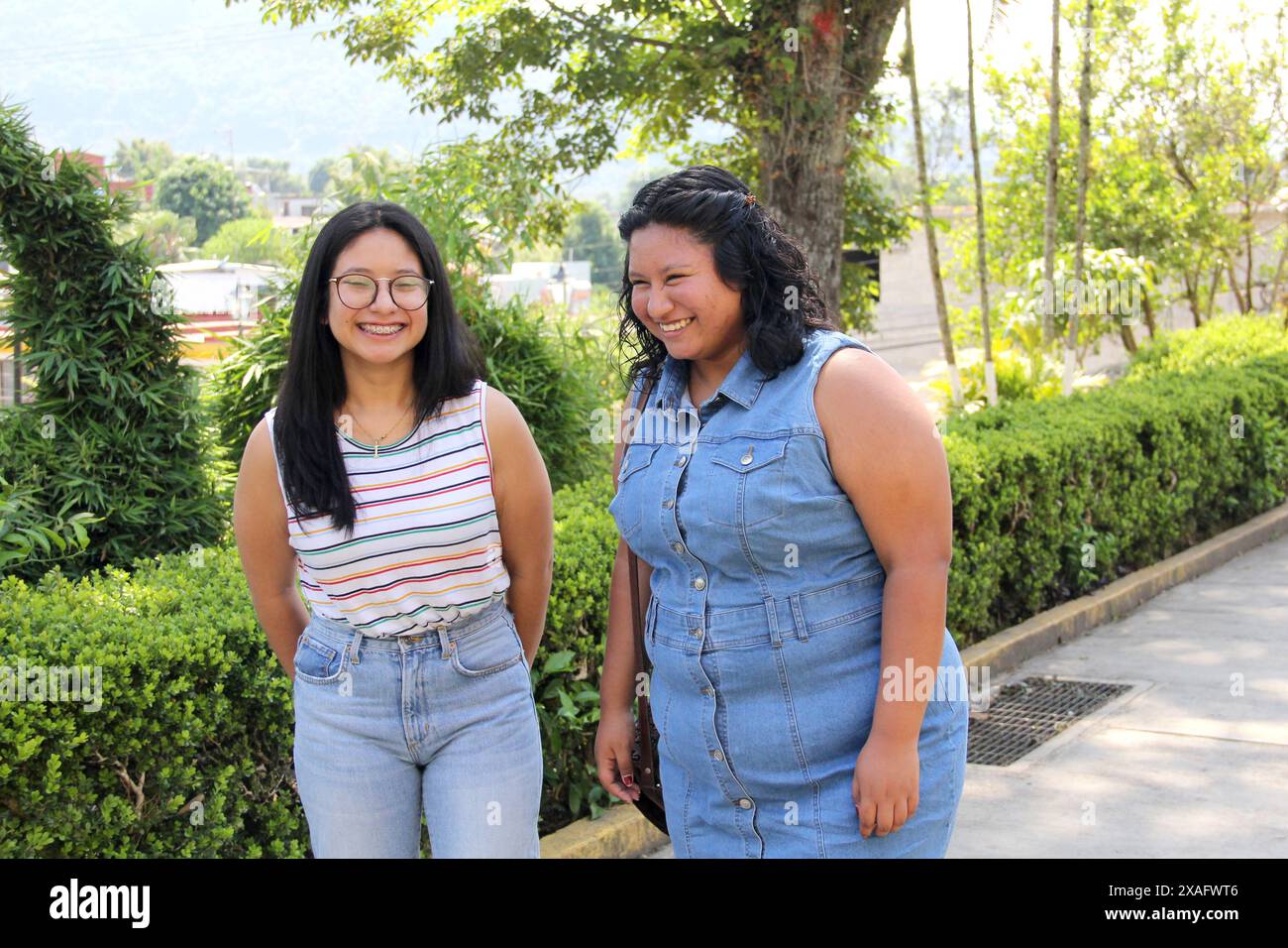 Two young women sisters and brunette latin friends walk and talk in the ...