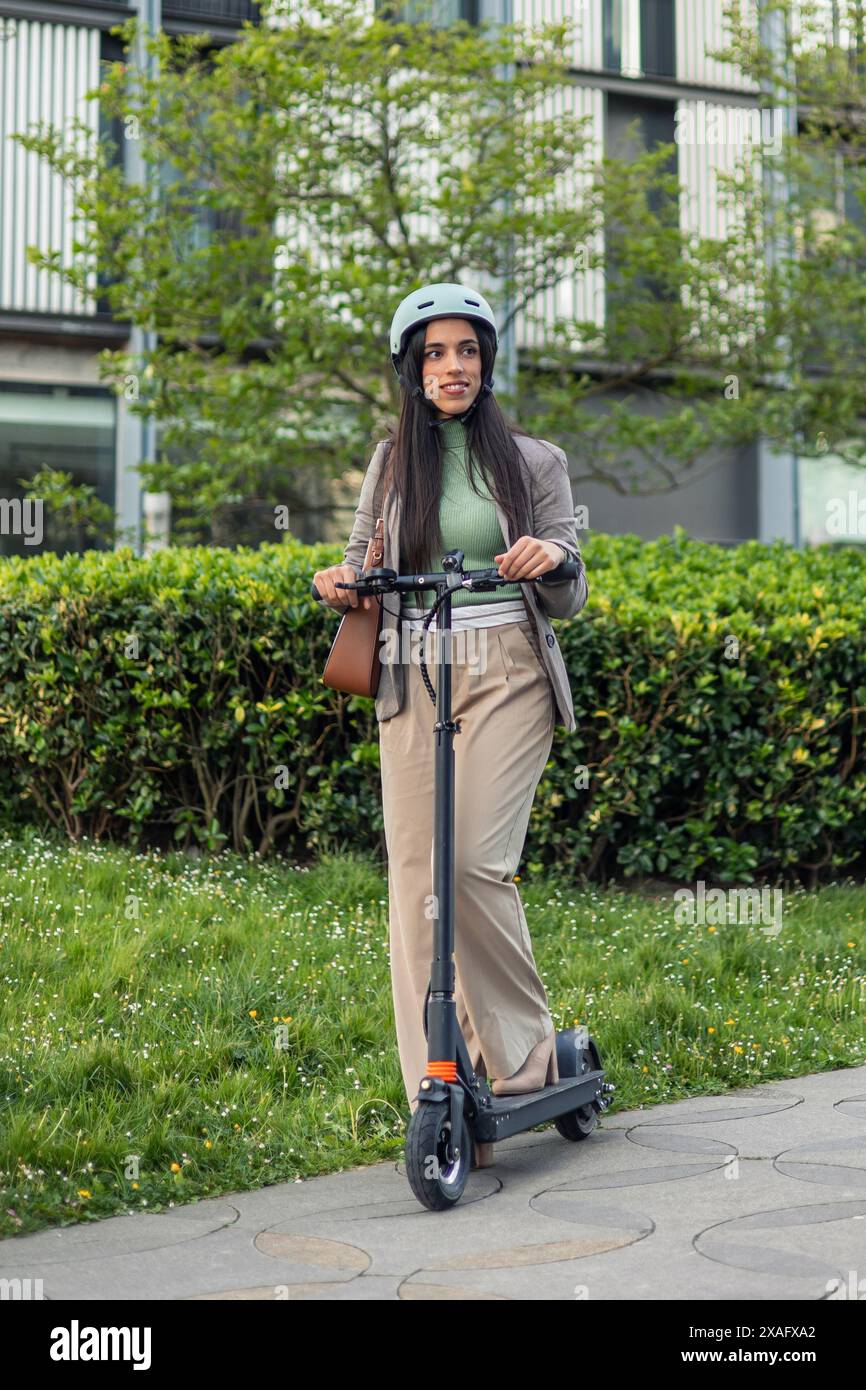 vertical businesswoman stands next to her electric scooter, symbolizing ...