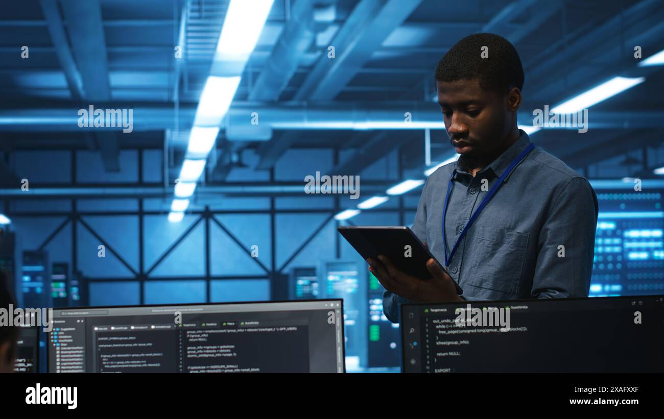 Technician in server hub using tablet to find hardware misconfigurations affecting rackmounts ...