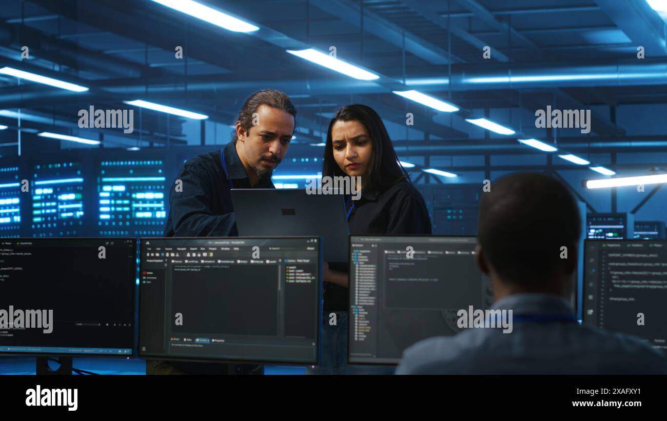 Multiethnic engineering team in server hub monitoring data center energy consumption across ...