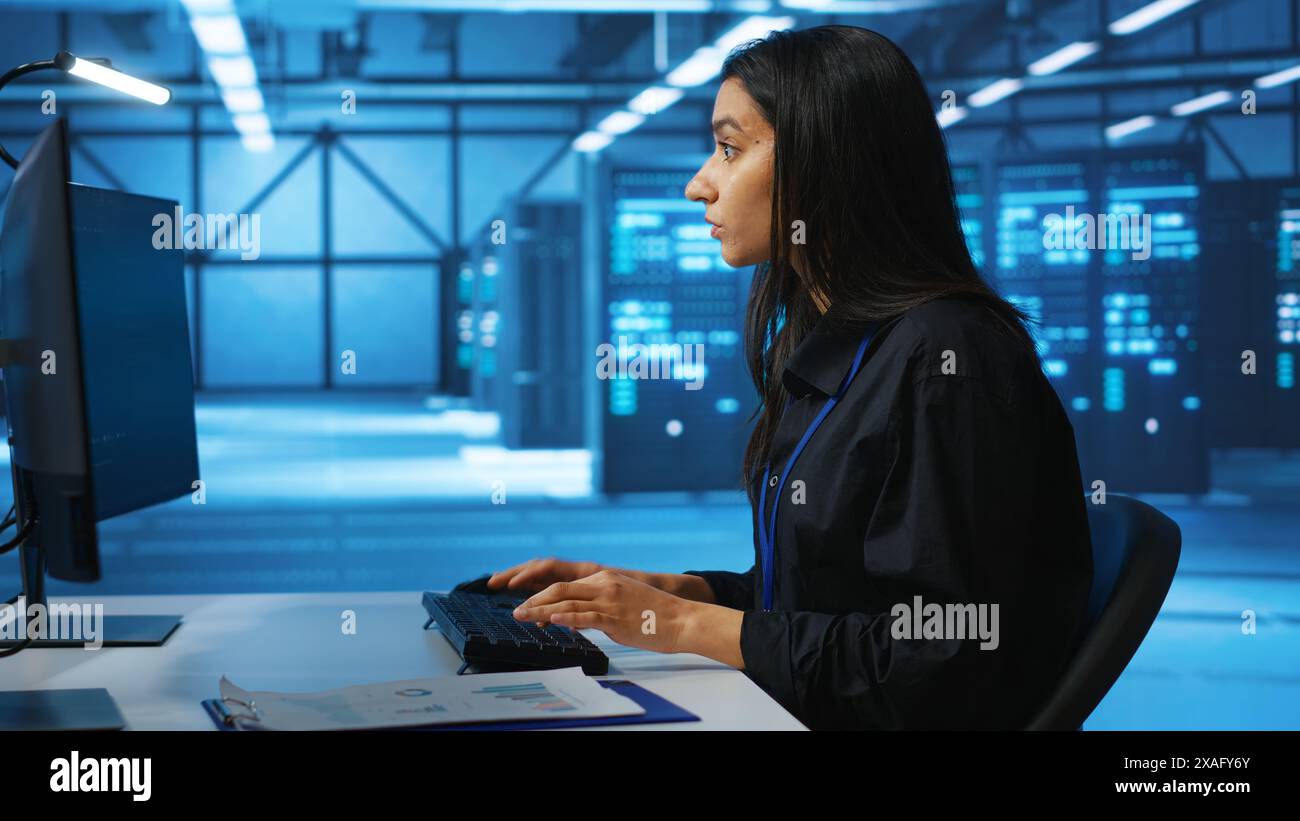 IT engineer looking at PC screen, working in network security data center, ensuring optimal ...