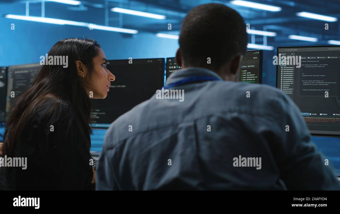 Diverse IT engineers in server room brainstorming ways to fix equipment storing datasets ...