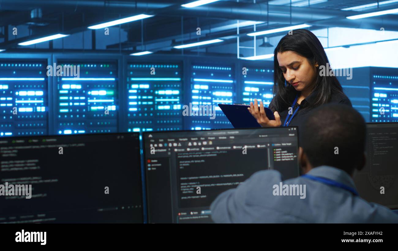 Manager overseeing server room, walking around with checklist on ...