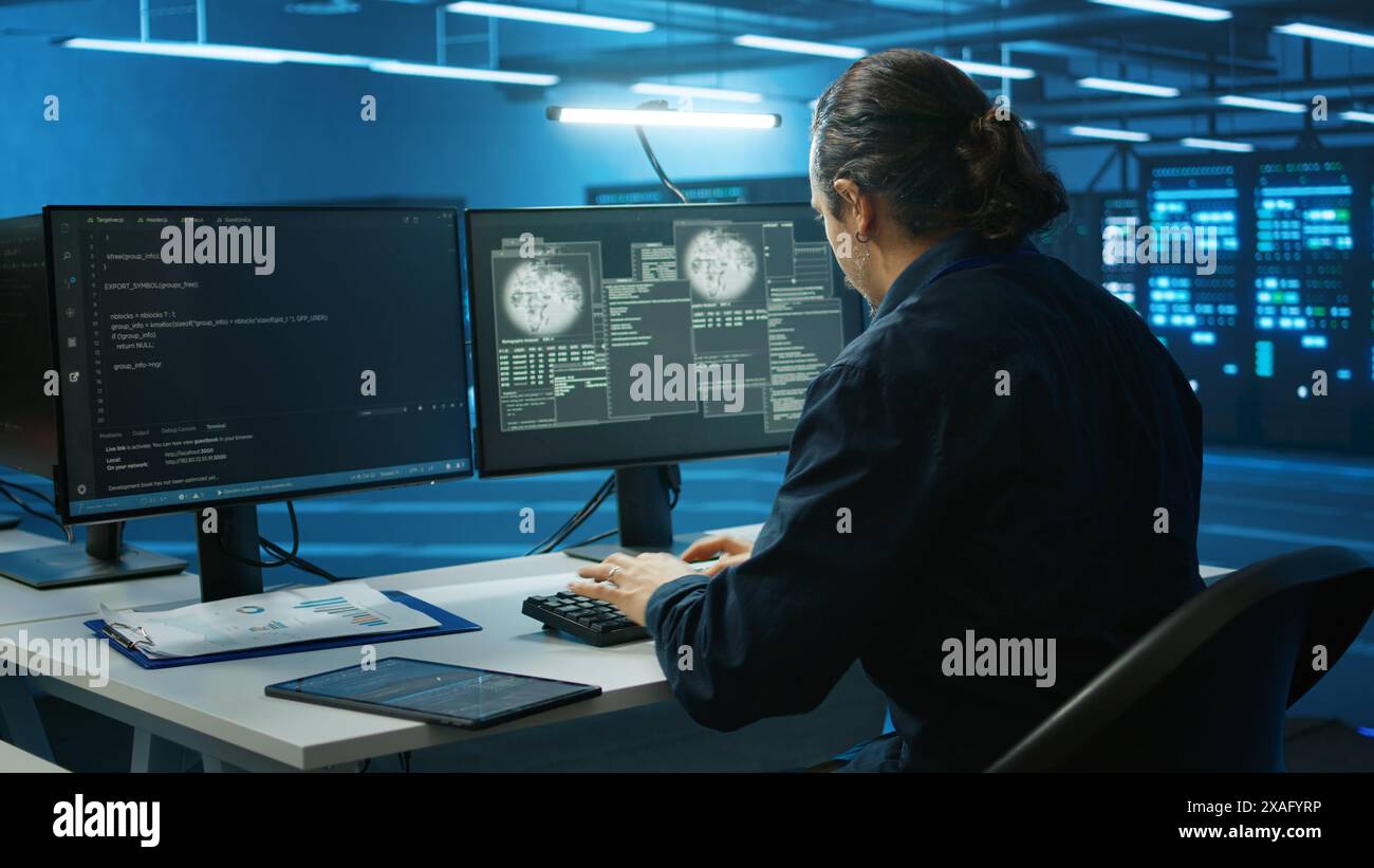 System administrator in server room frightened by sensitive data threatened by hacking attack on ...