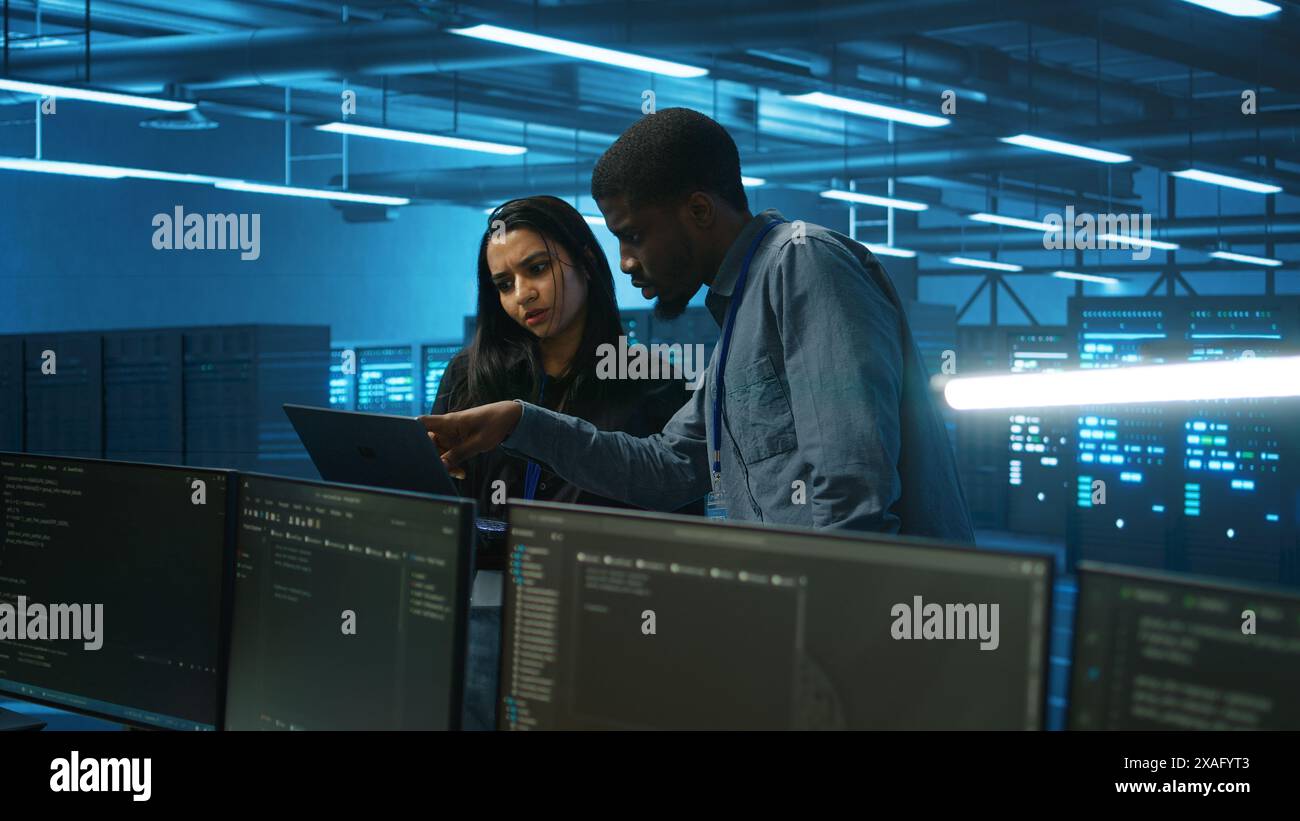 Coworking technicians looking at laptop screen, working in data center ...