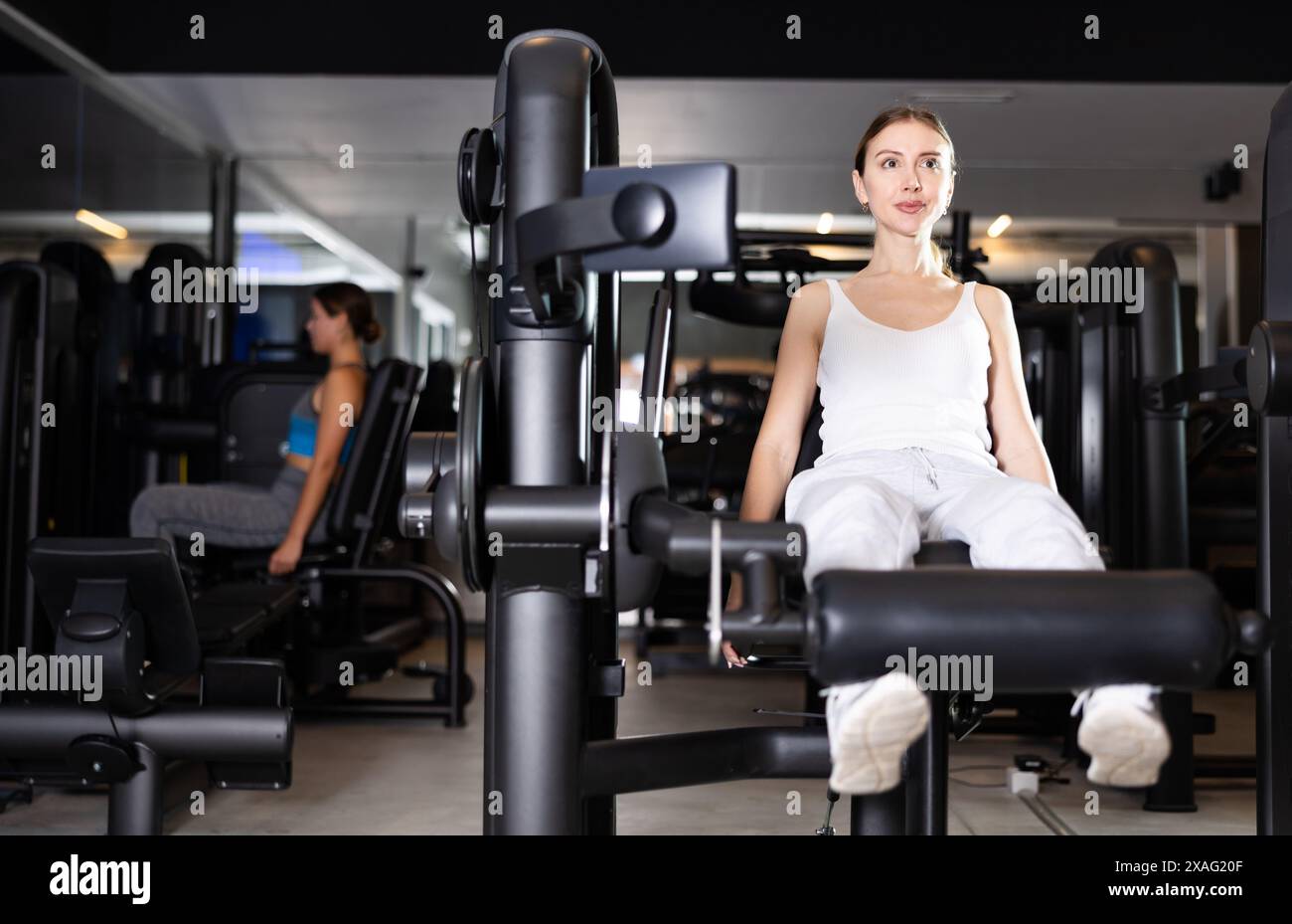 Sportive young girl training on leg extension machine in gym Stock ...