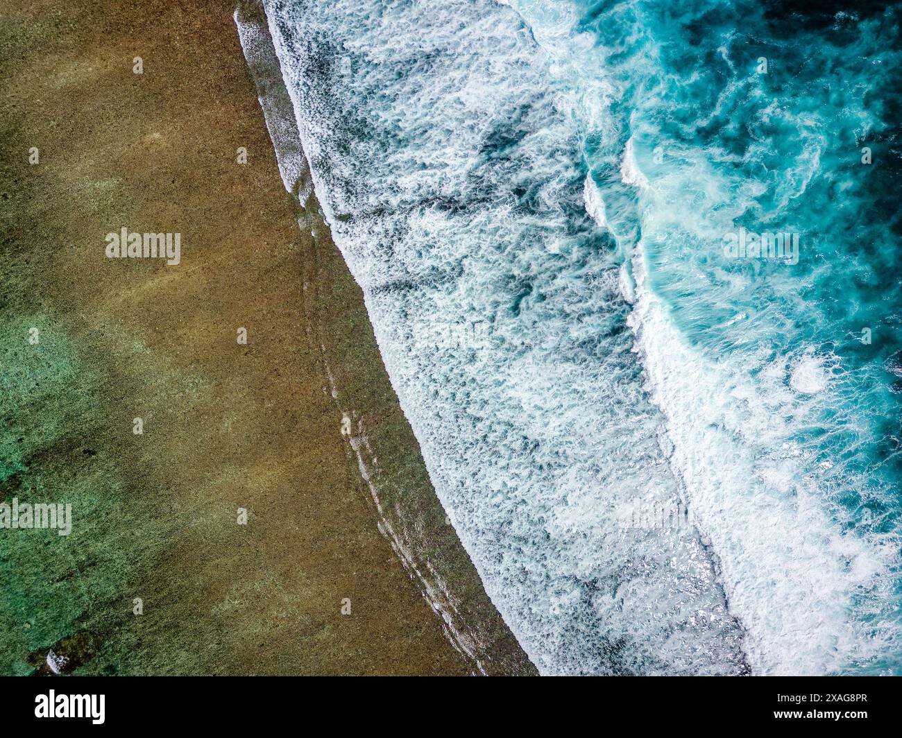 Top down aerial view of ocean waves breaking against a shallow tropical ...