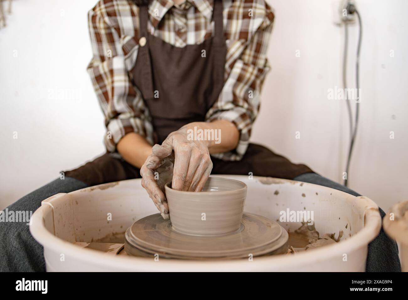 Female potter creating ceramic dish on potter's wheel using hands ...