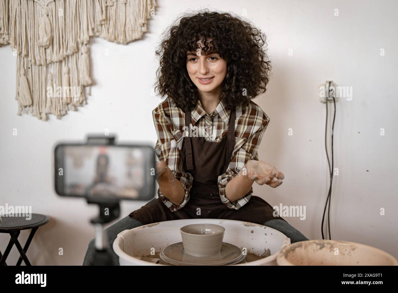 Young woman potter sculpts pottery using a potter's wheel while ...