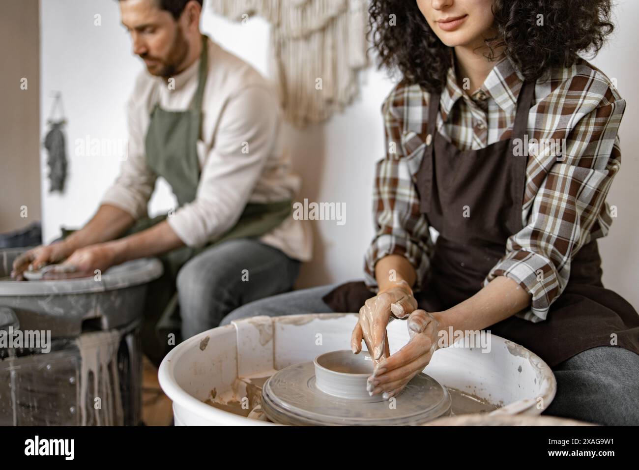 Man and woman working together creating pottery using clay on potter's ...