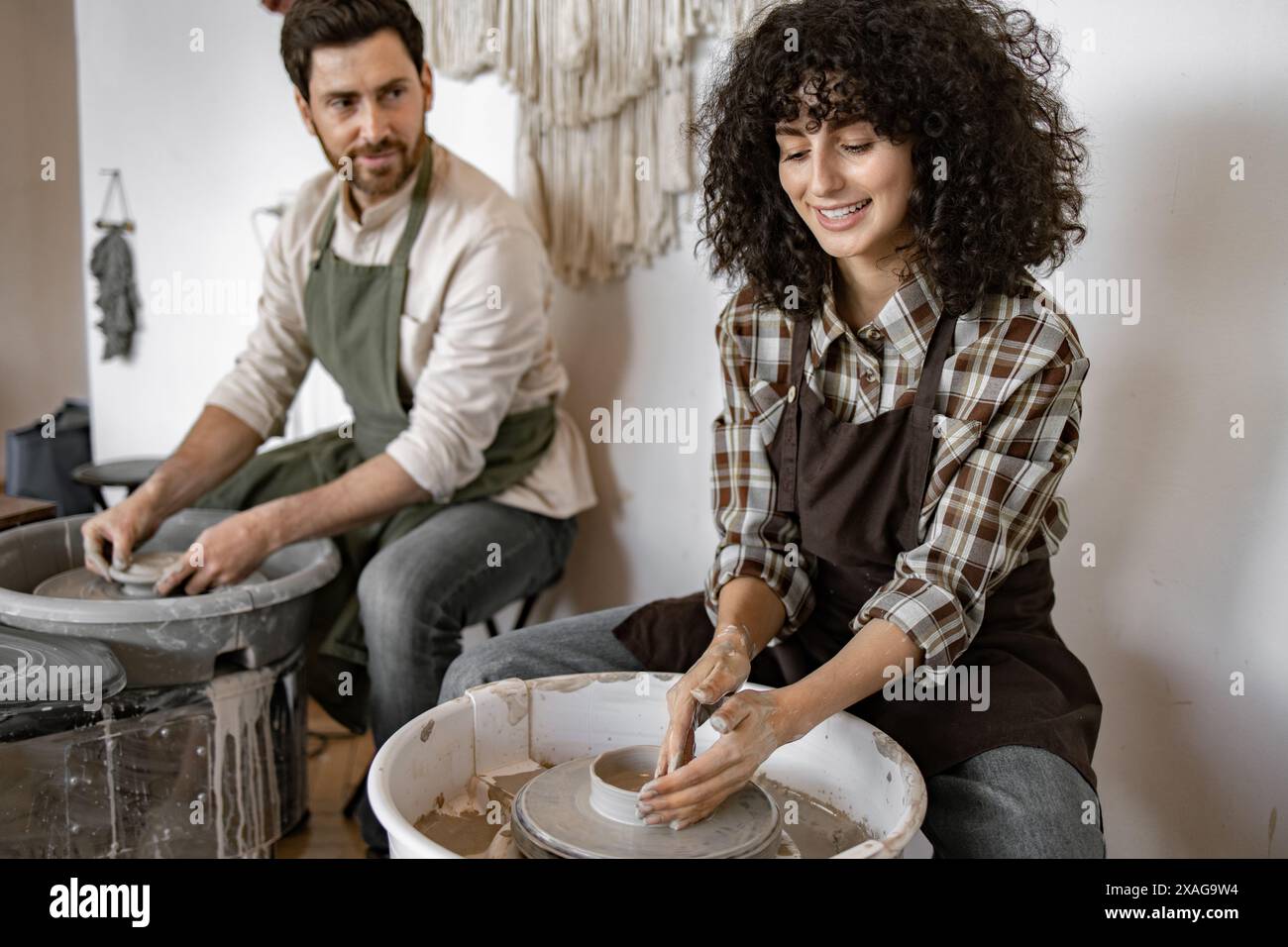 Man and woman potters working together on pottery wheel to create clay ...