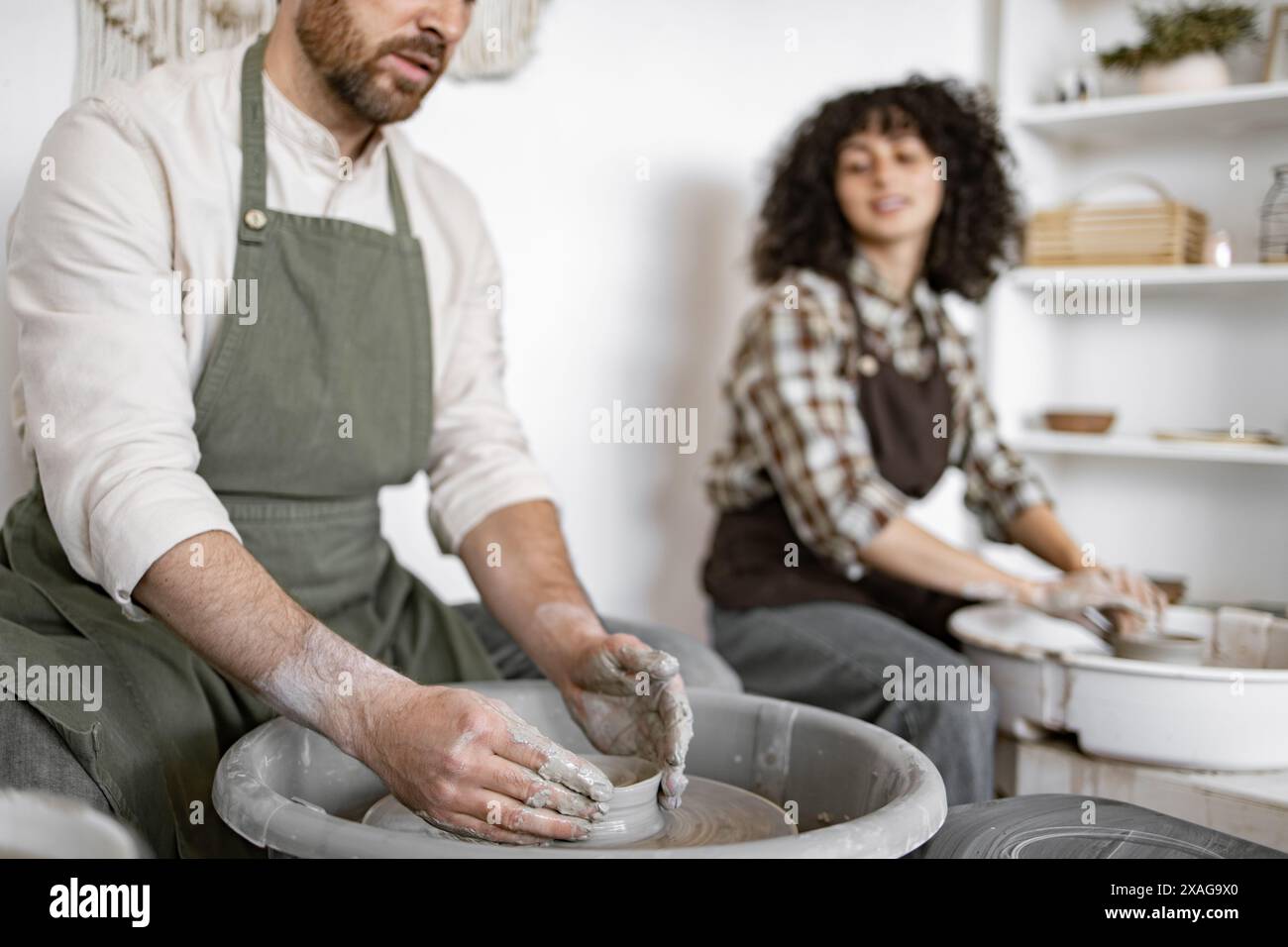 Man and woman potters using pottery wheels to craft clay vases in ...