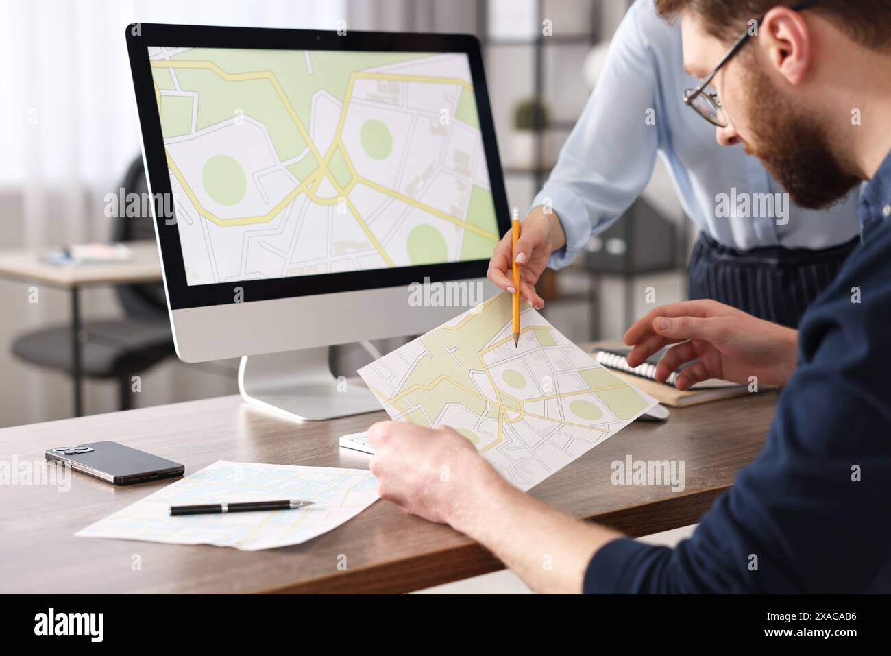 Cartographers working with cadastral maps at wooden table in office ...