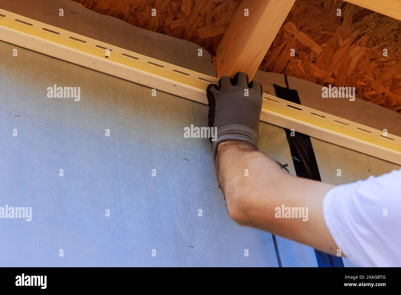 Craftsman nails J-channel vinyl trim before installing for siding in ...