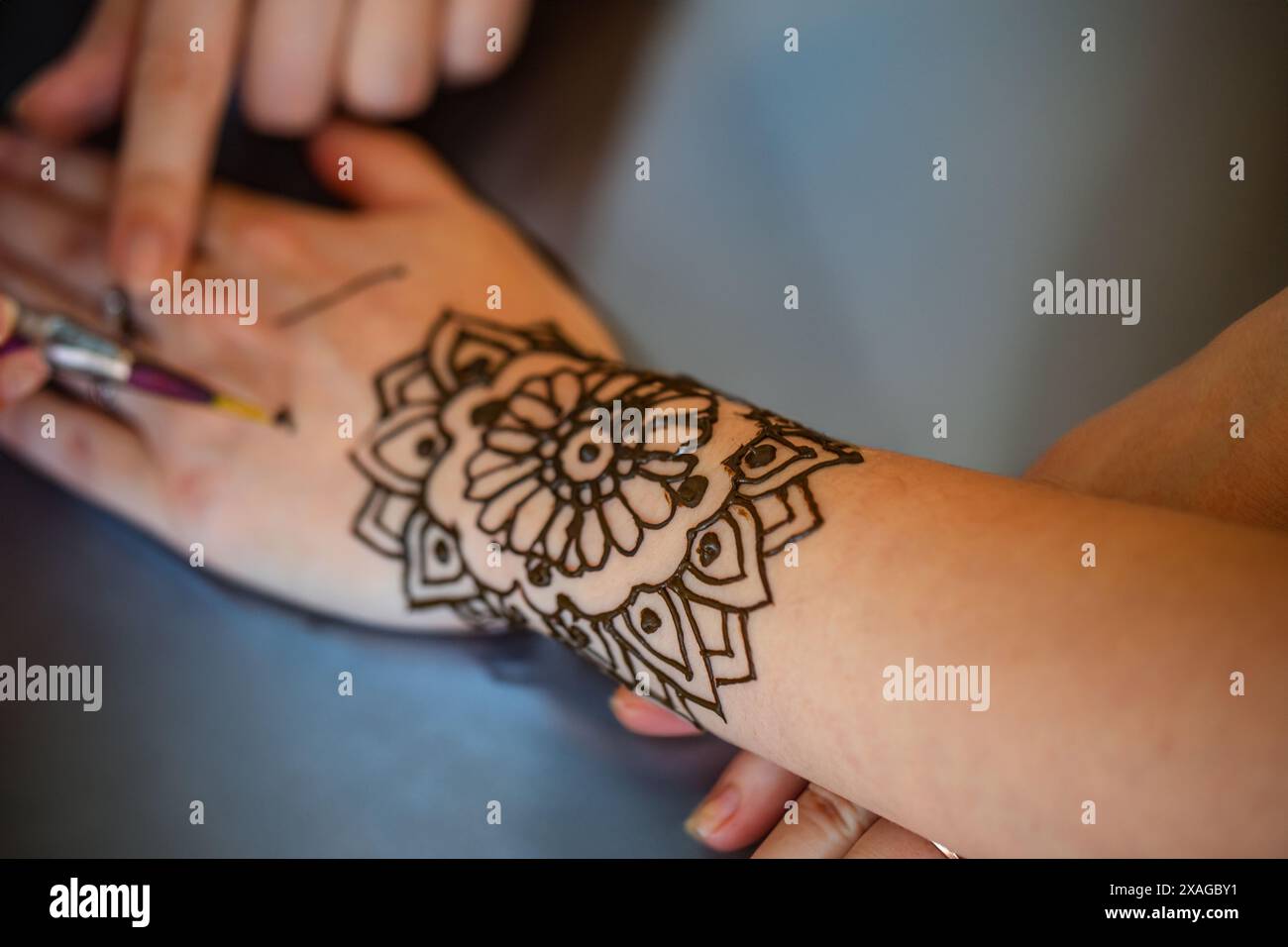 This image shows a close-up of a womans wrist as a henna tattoo artist ...