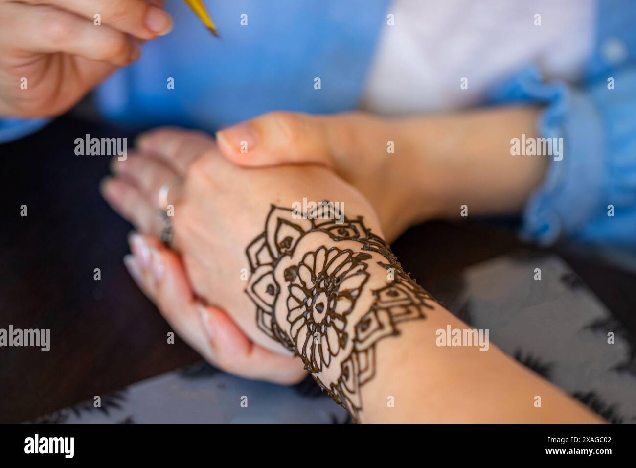 This image shows a close-up of a womans wrist as a henna tattoo artist ...