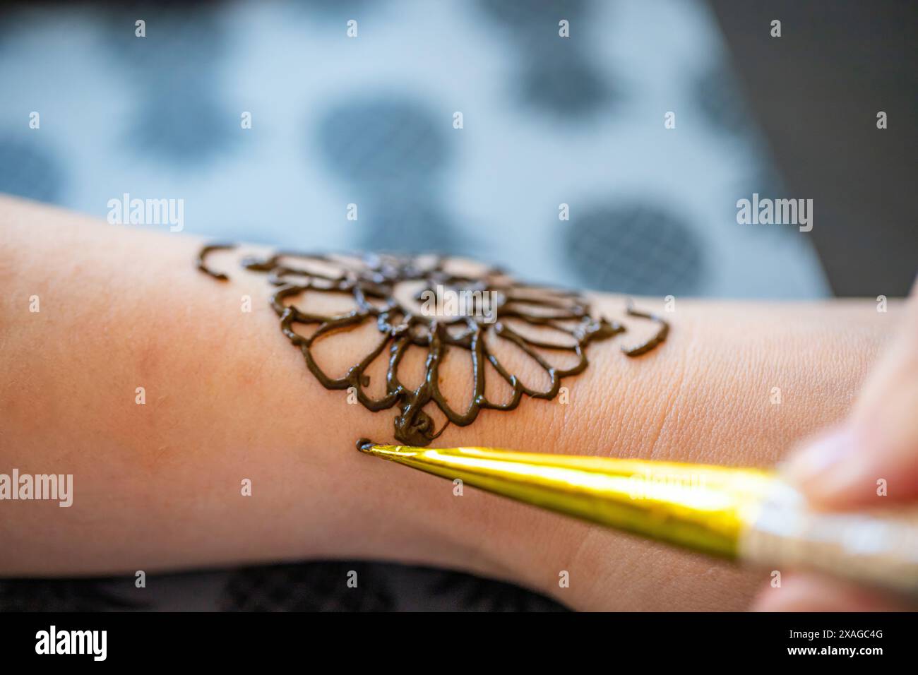 This image shows a henna artist applying an intricate floral design on ...