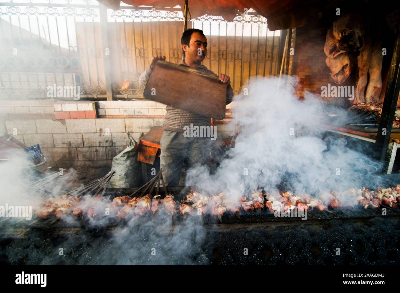 An Uyghur man grilling kebabs ( meat skewers ) in the old city of ...