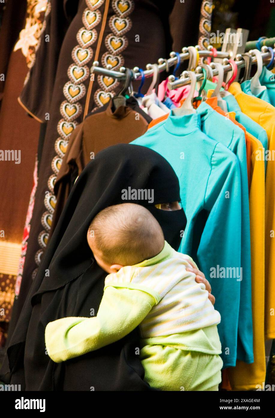 A veiled Egyptian woman holding her baby in the bazaar in Islamic Cairo ...