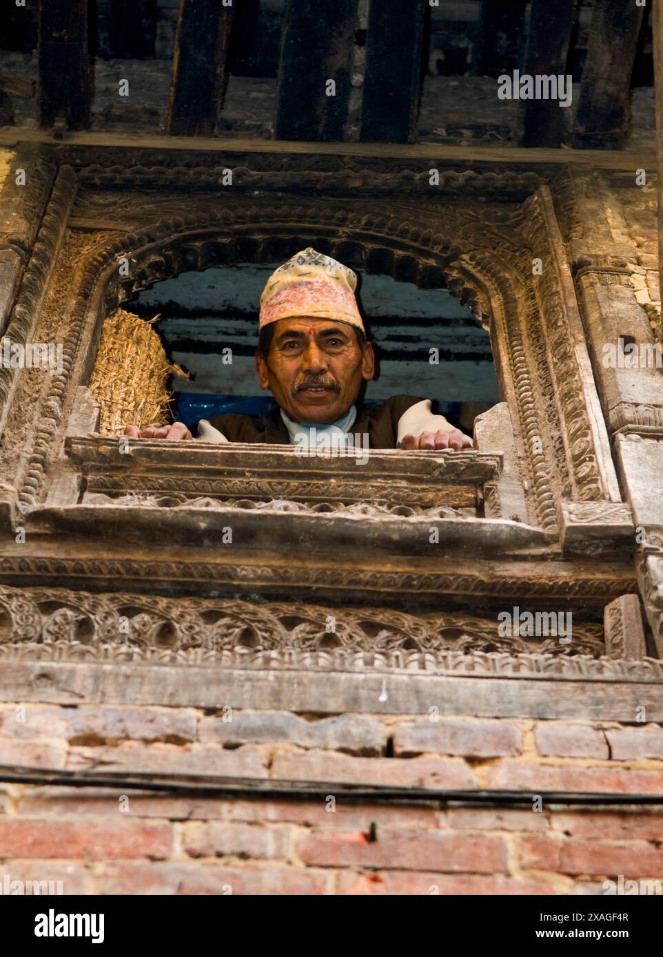 Portrait of a Nepali man looking out the window of his house in ...