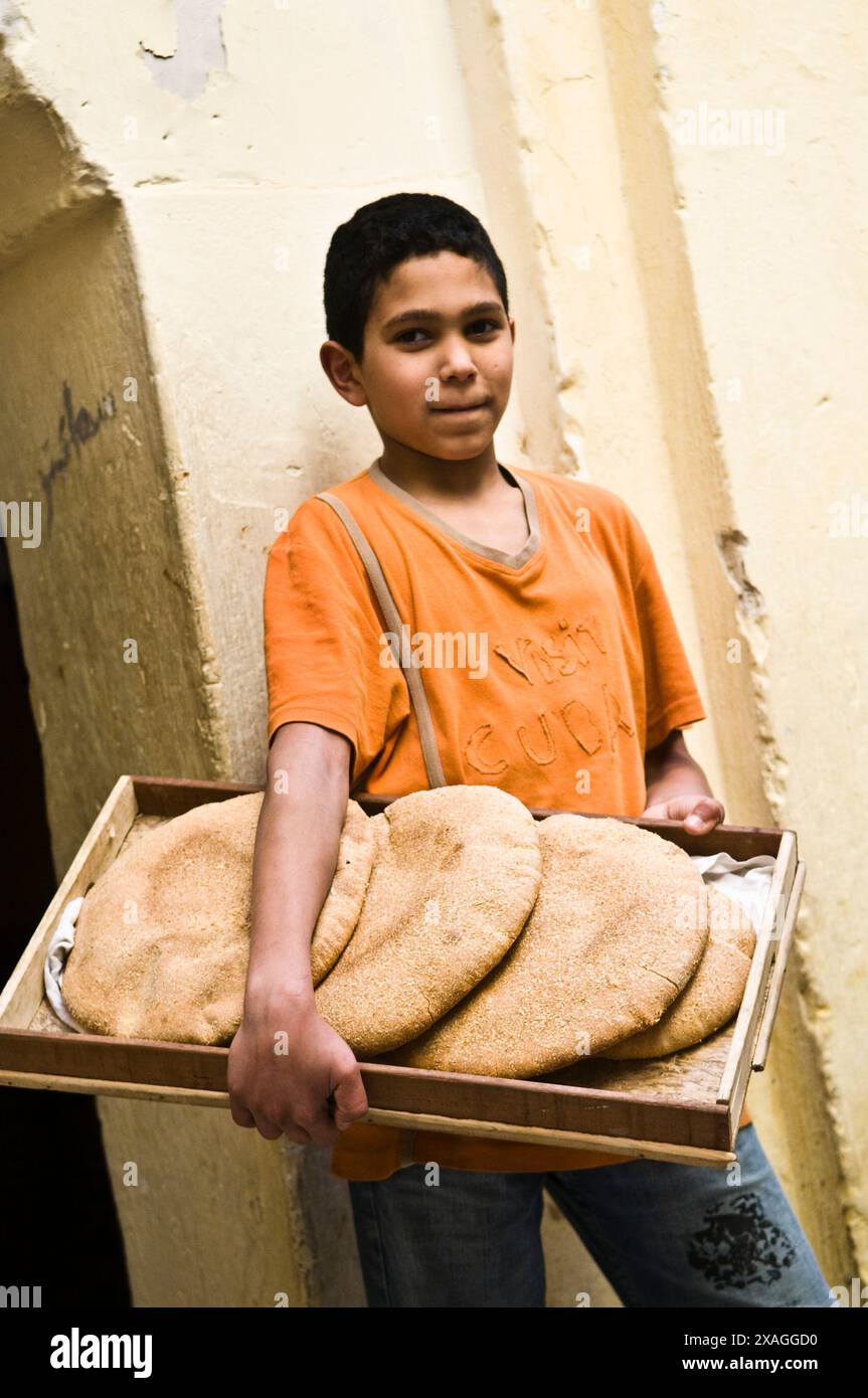 A Moroccan boy carrying traditional Moroccan Pita bread out of a bakery ...