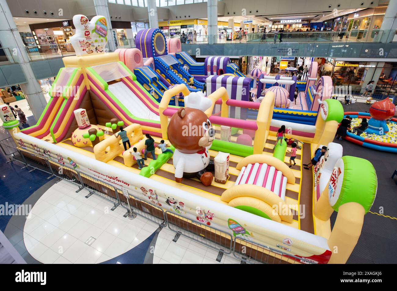 Inside a spacious shopping mall interior. A huge bouncy castle is set ...