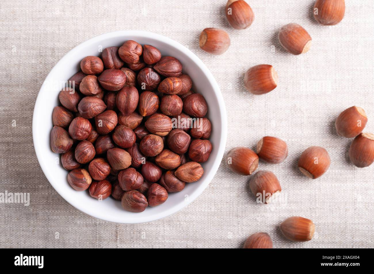 Hazelnuts in a white bowl on linen fabric. Whole, dried and shelled ...