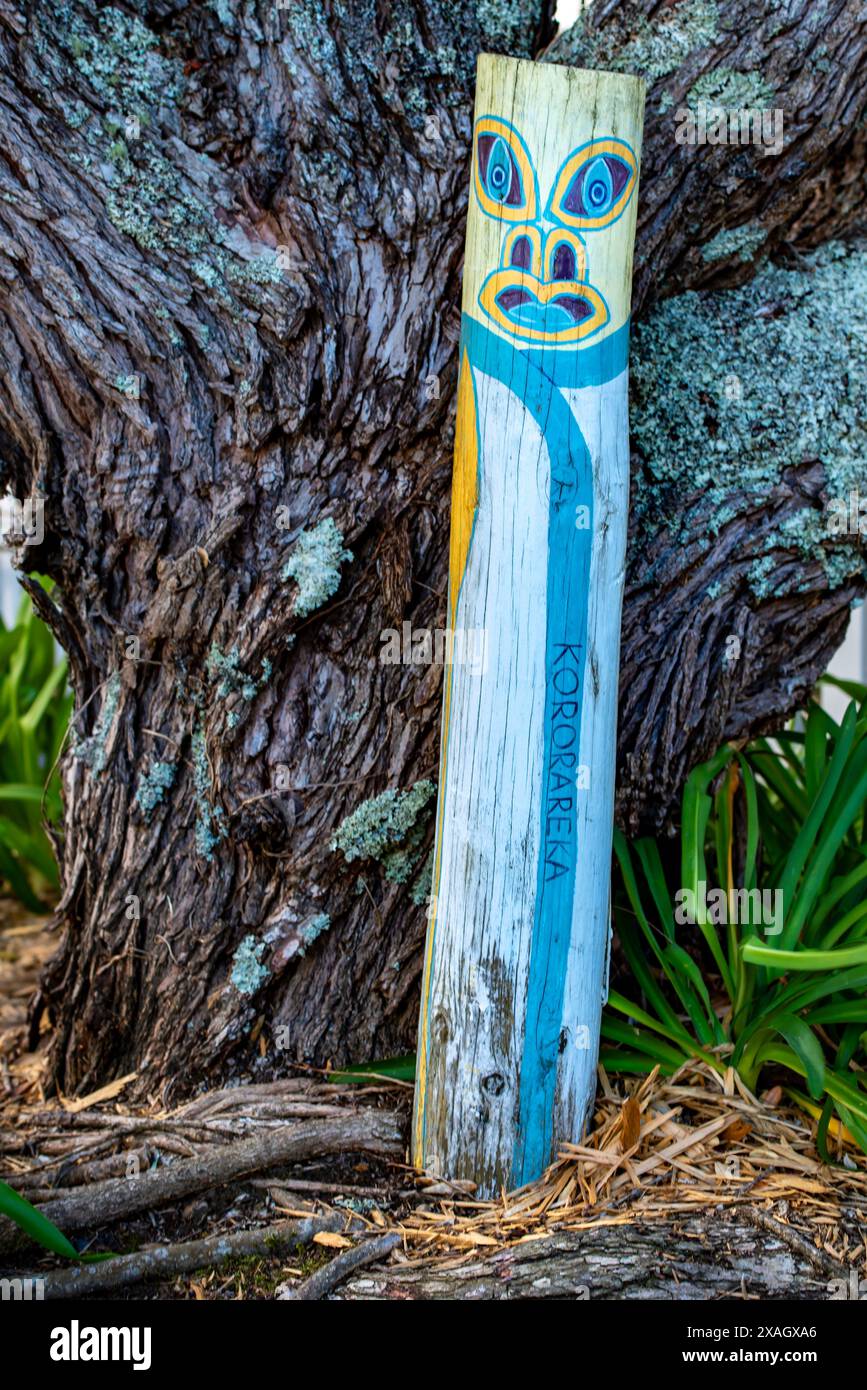 A mini totem, painted not carved, beside a tree in the village of ...