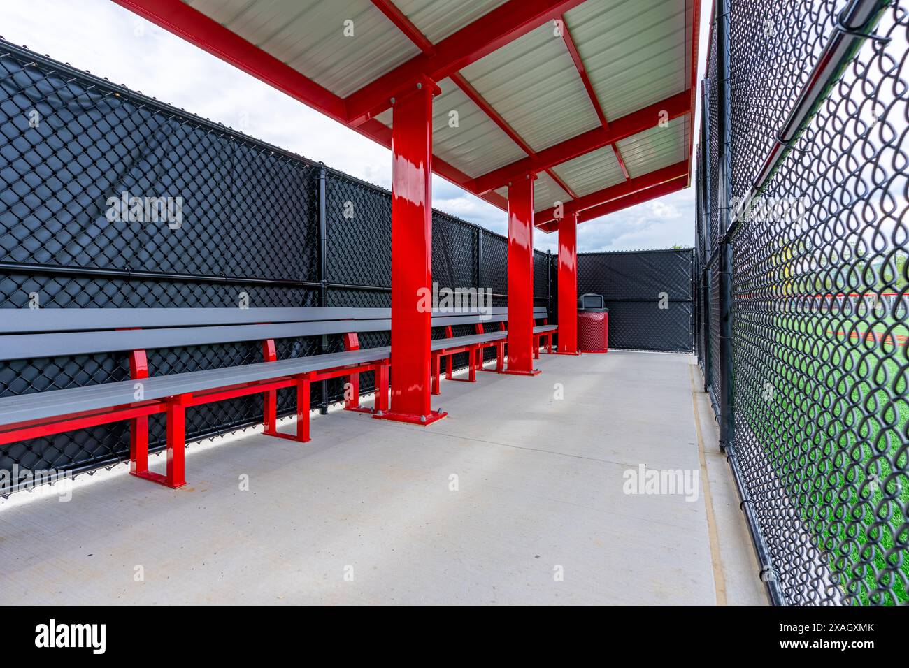 Interior photo of a red softball baseball dugout with roof, concrete ...