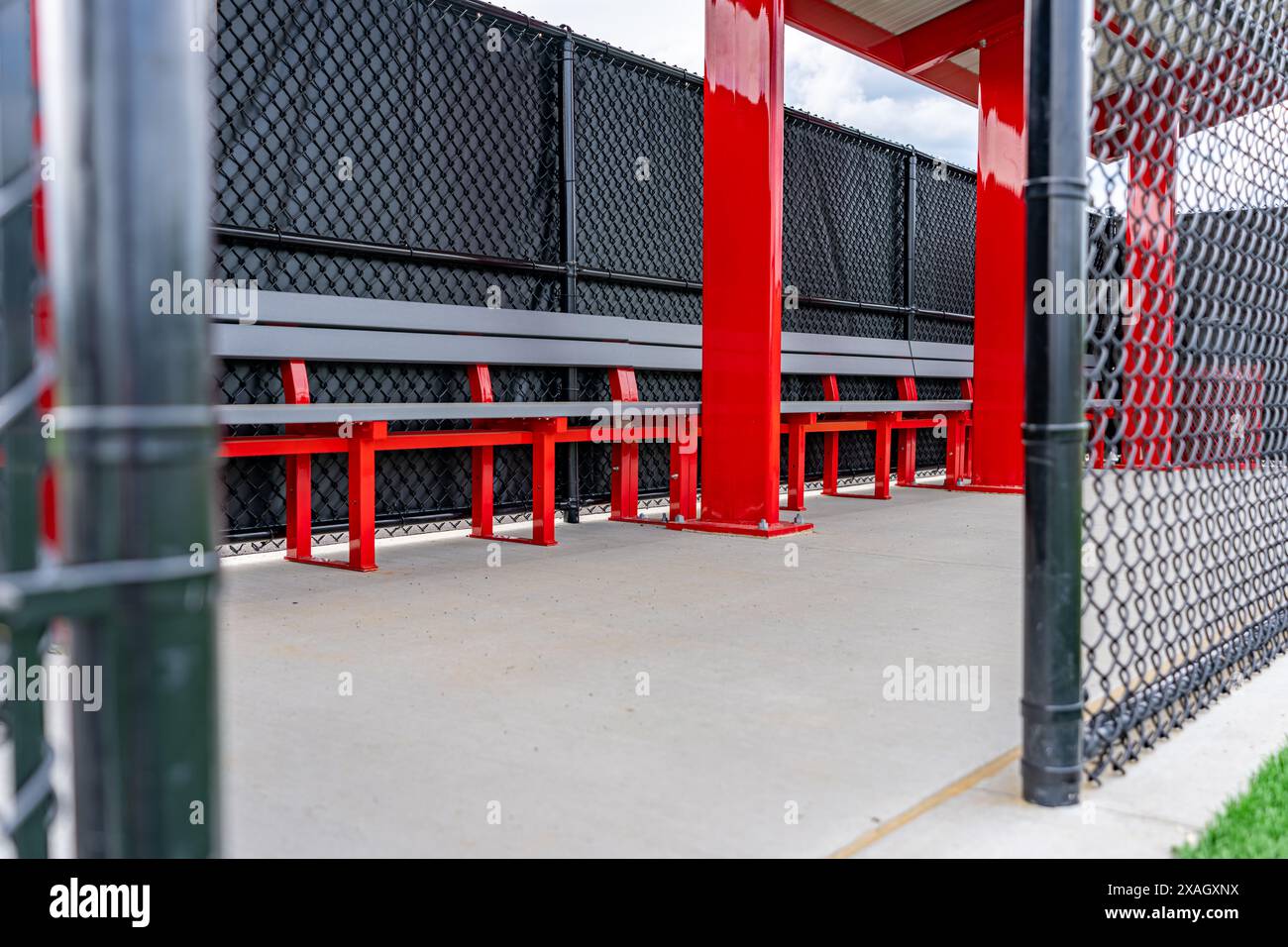 Interior photo of a red softball baseball dugout with roof, concrete ...