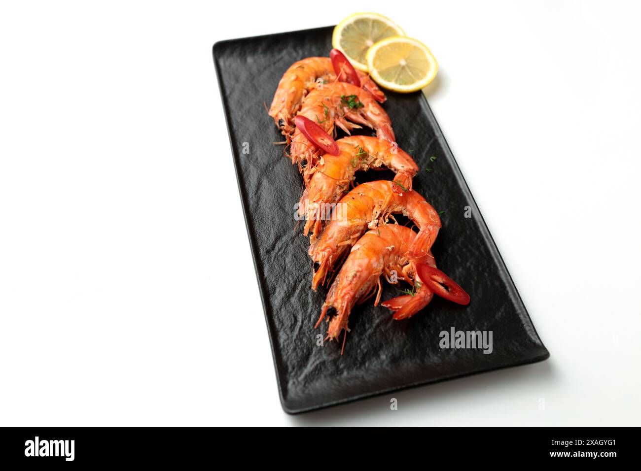 Large cooked king prawns on a black plate. Isolated background Stock ...