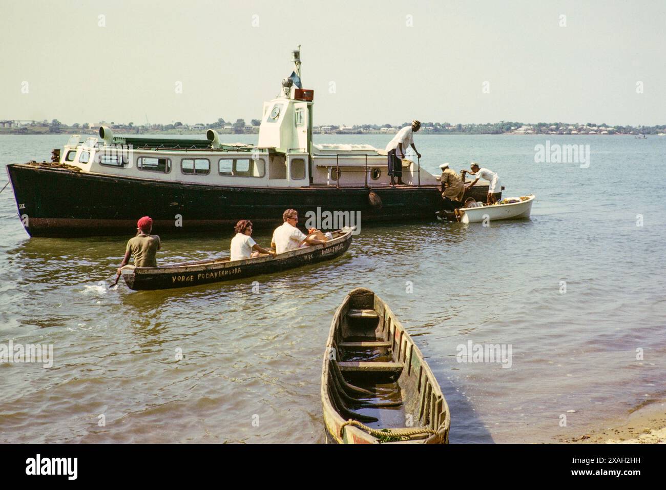 Expatriates on beach with pirogue canoe and boat for trip to Bunce ...