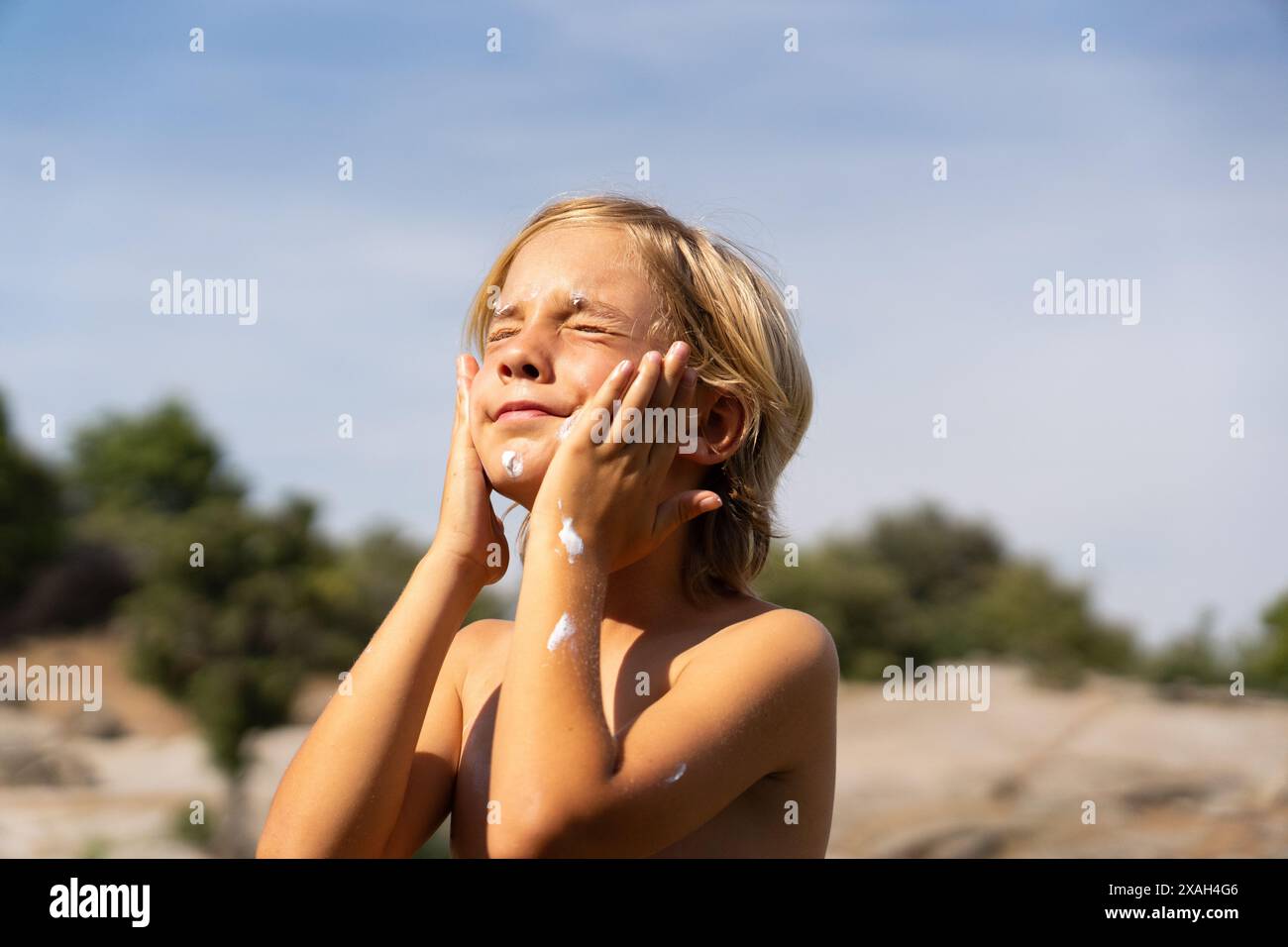 Caucasian boy putting sun cream on his face in nature Stock Photo - Alamy