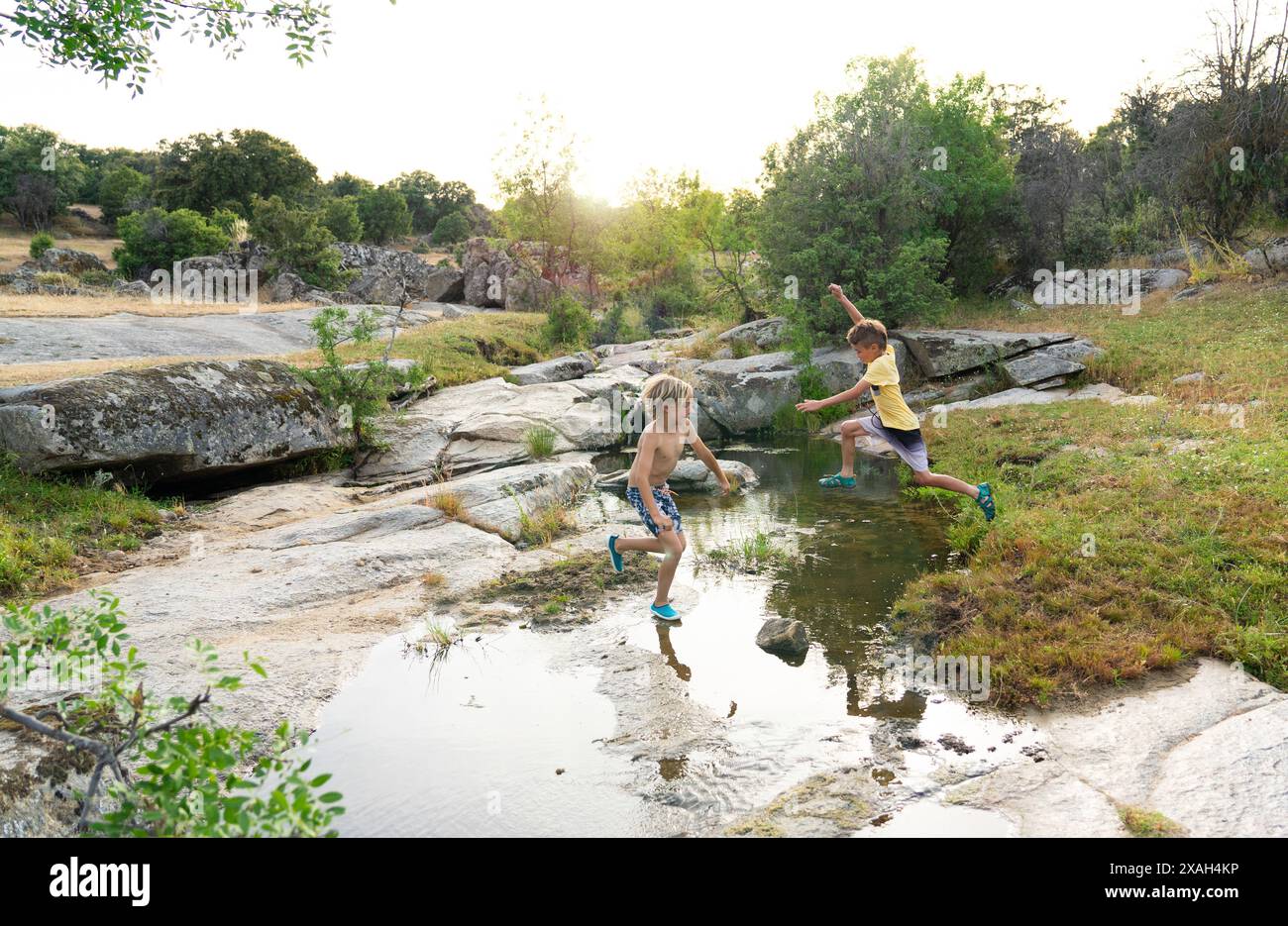 Two Caucasian children playing in summer in nature jumping over a ...